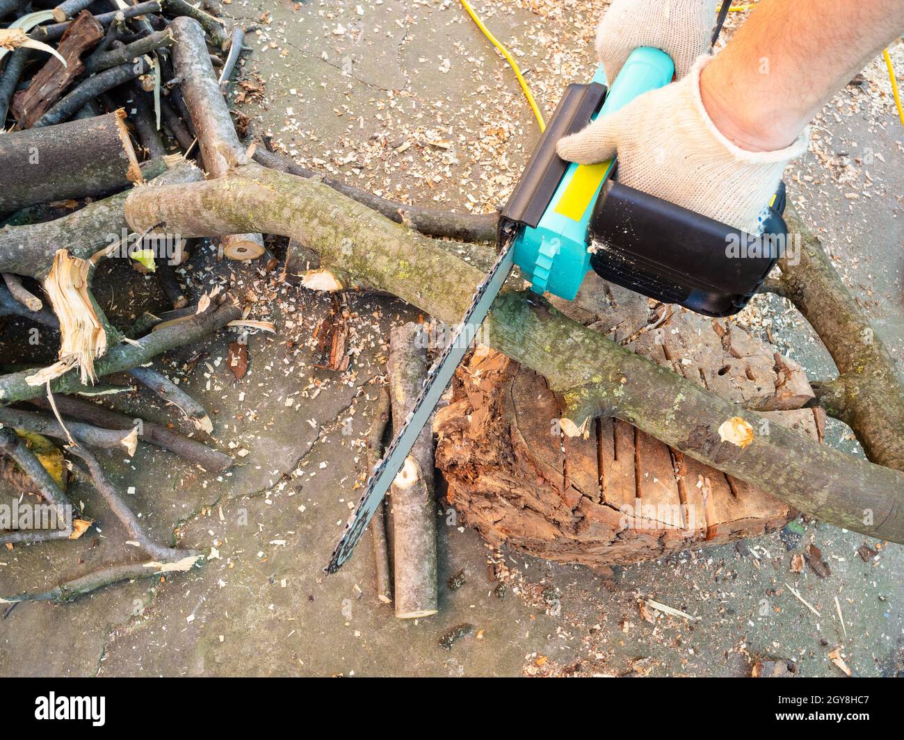 above view of sawing tree branches with electric chain saw in backyard ...