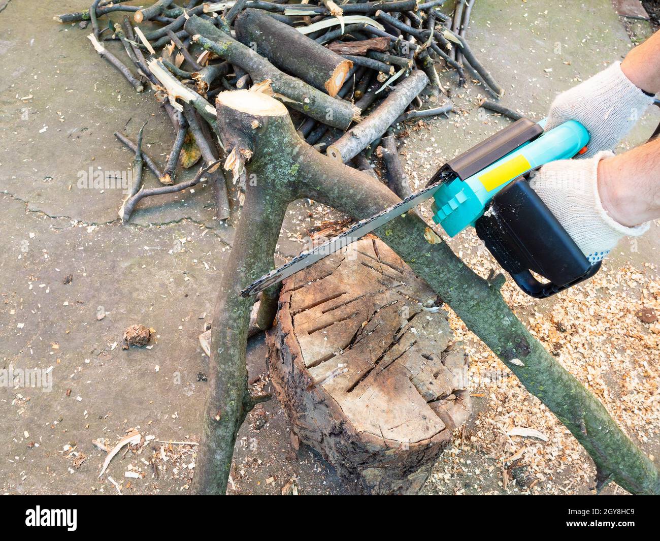 above view of sawing tree limbs with electric chain saw in backyard ...