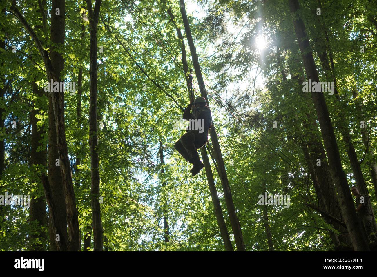 a man in military outfit zip lining inside of a forest Stock Photo - Alamy