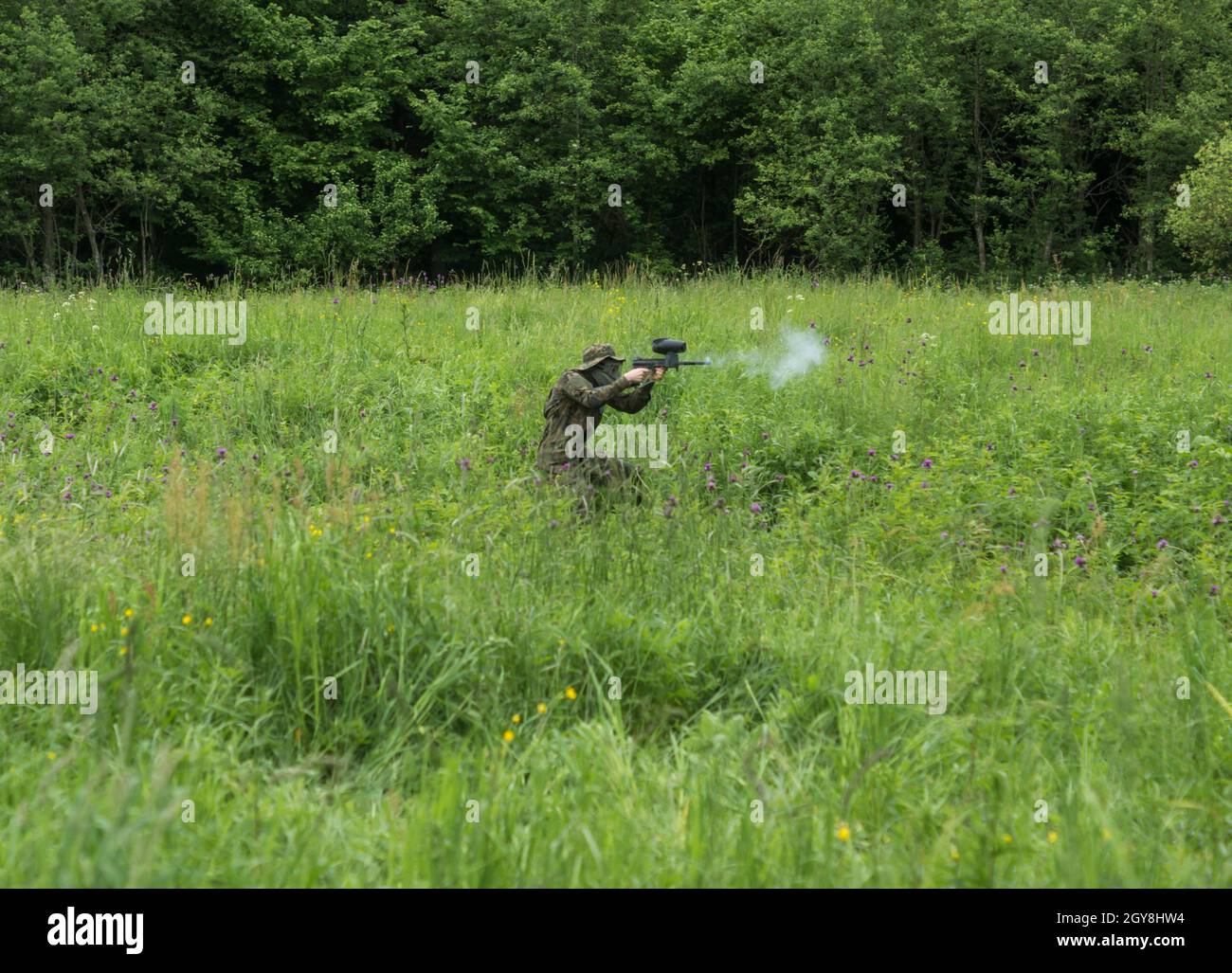group of masked people playing paintball in forest Stock Photo - Alamy
