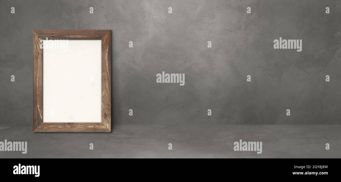 Wooden picture frame leaning on a grey wall. Blank mockup template ...