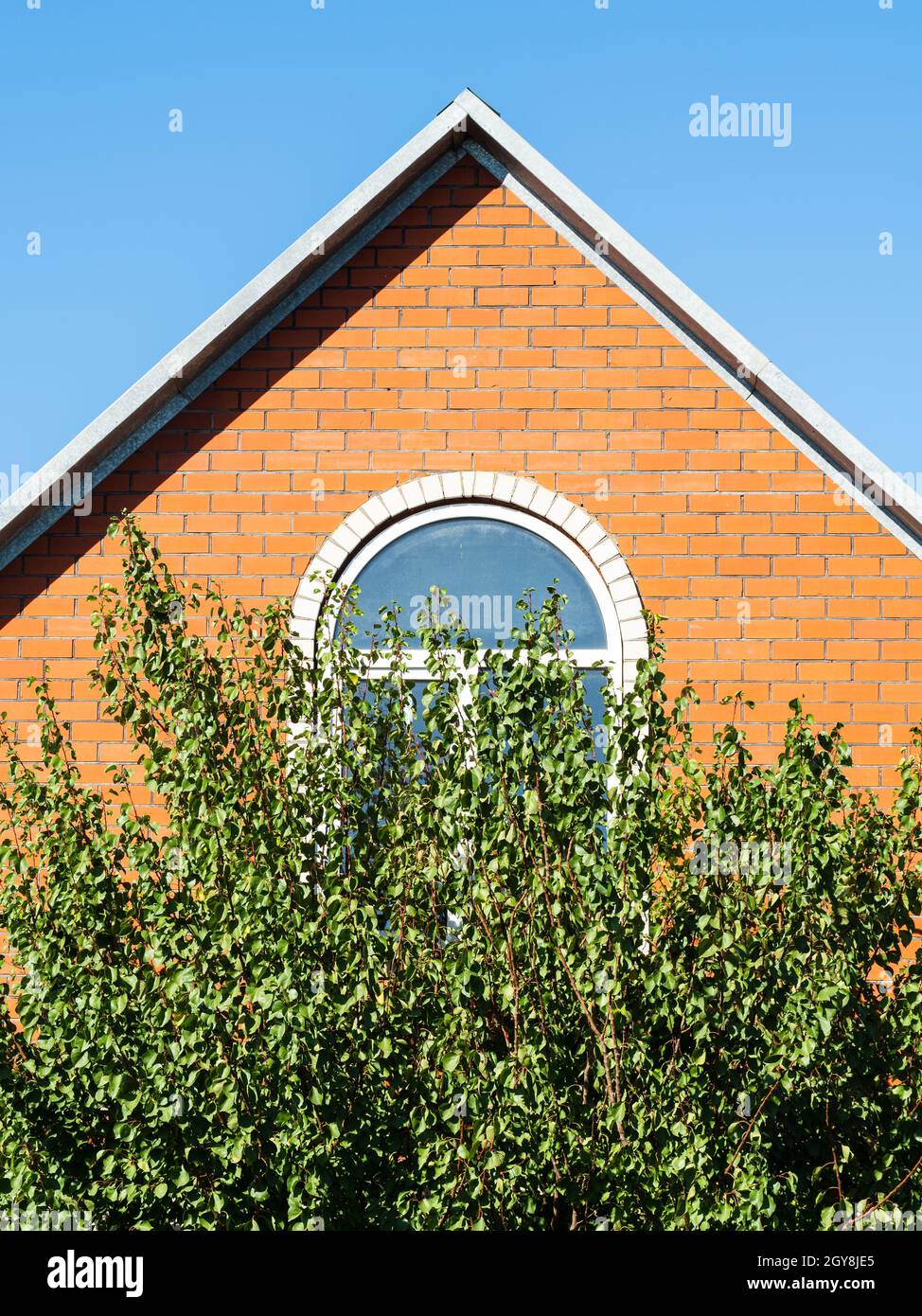 front view of brick gable wall of cottage and blue sky on sunny day ...