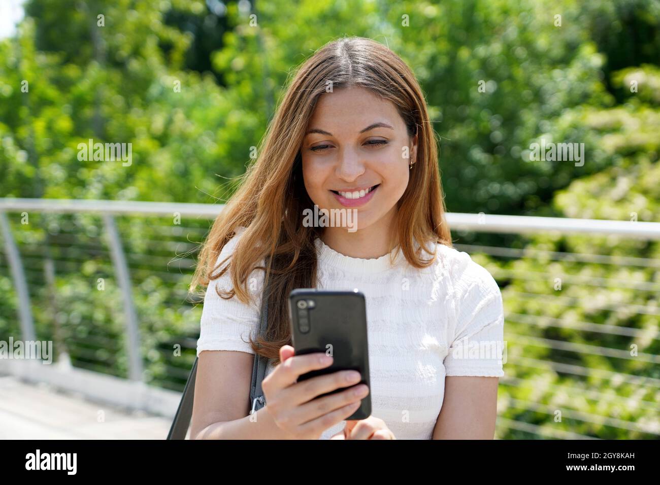 Happy beautiful young woman sending text message on cellphone outdoor ...