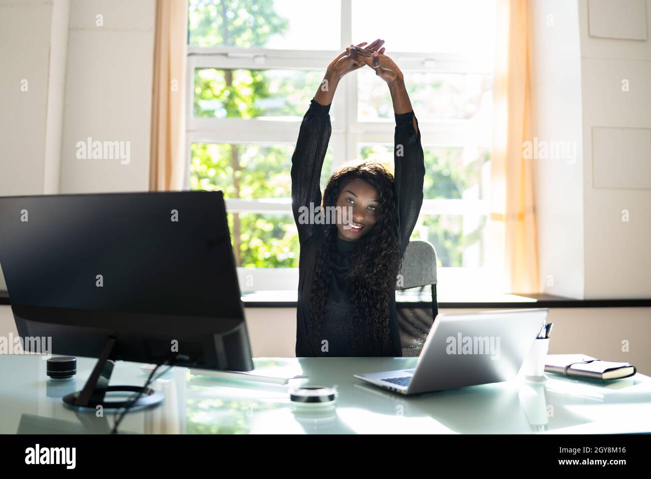 African Woman Stretching Exercise At Desk Working On Computer Stock ...