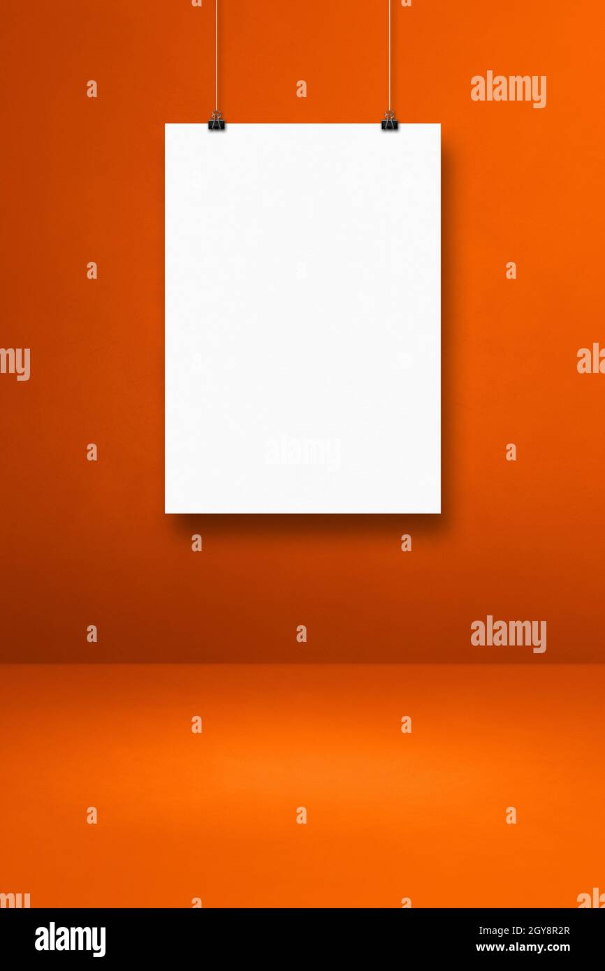 White poster hanging on an orange wall with clips. Blank mockup ...