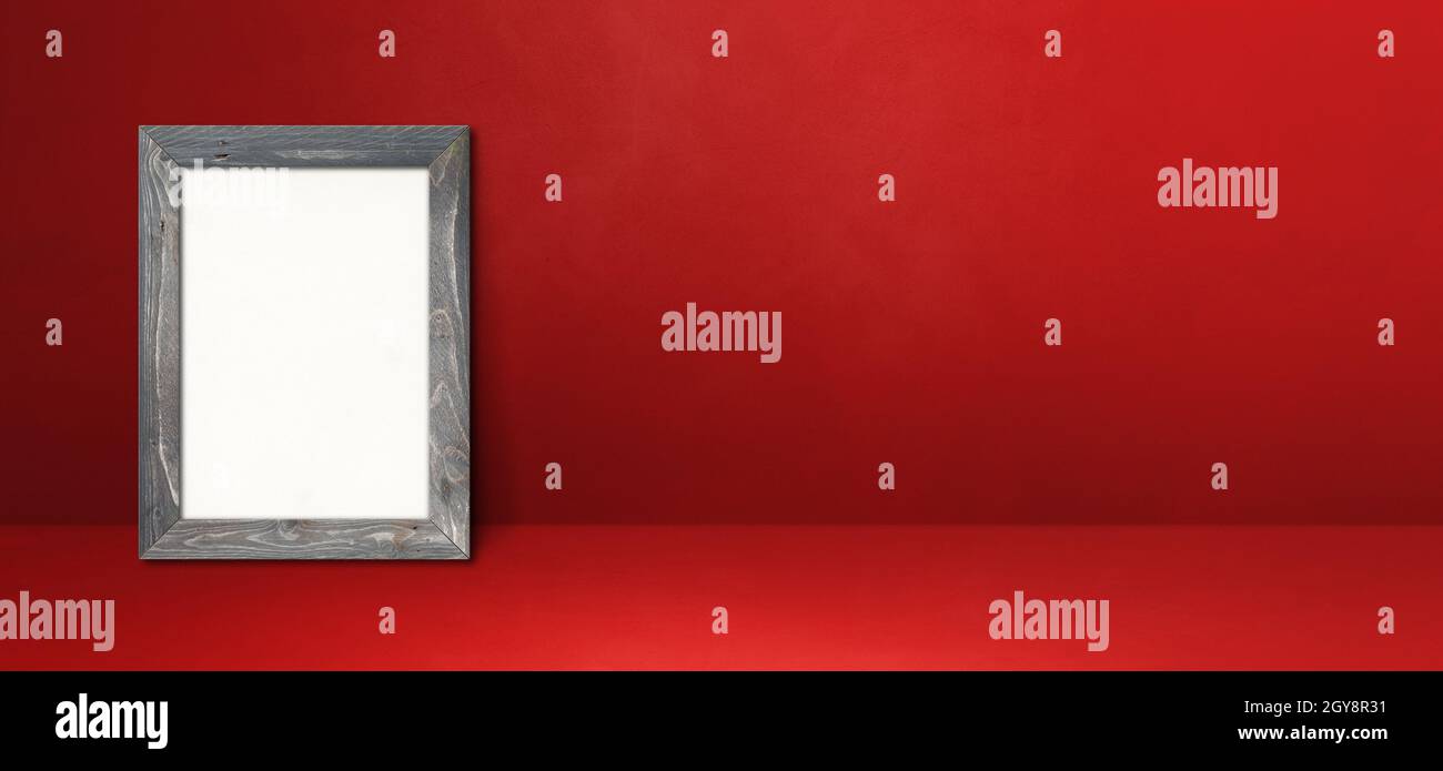 Wooden picture frame leaning on a red wall. Blank mockup template ...