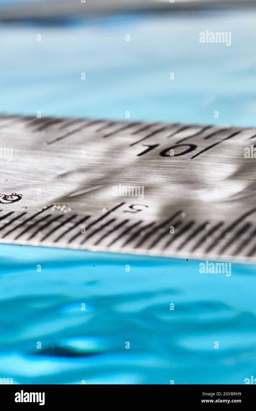 Silvery ruler is wet as it rests under a thin layer of aqua blue water ...