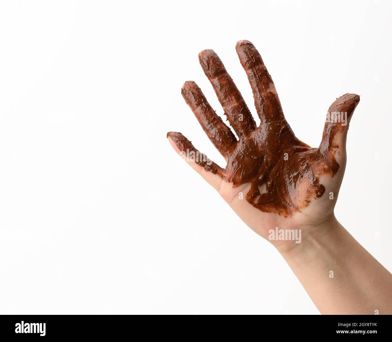 female hand soiled in melted black chocolate on a white background ...