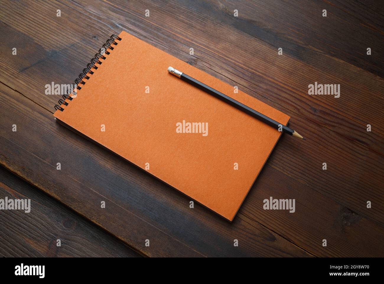 Orange notepad and pencil on wooden background. Blank stationery ...