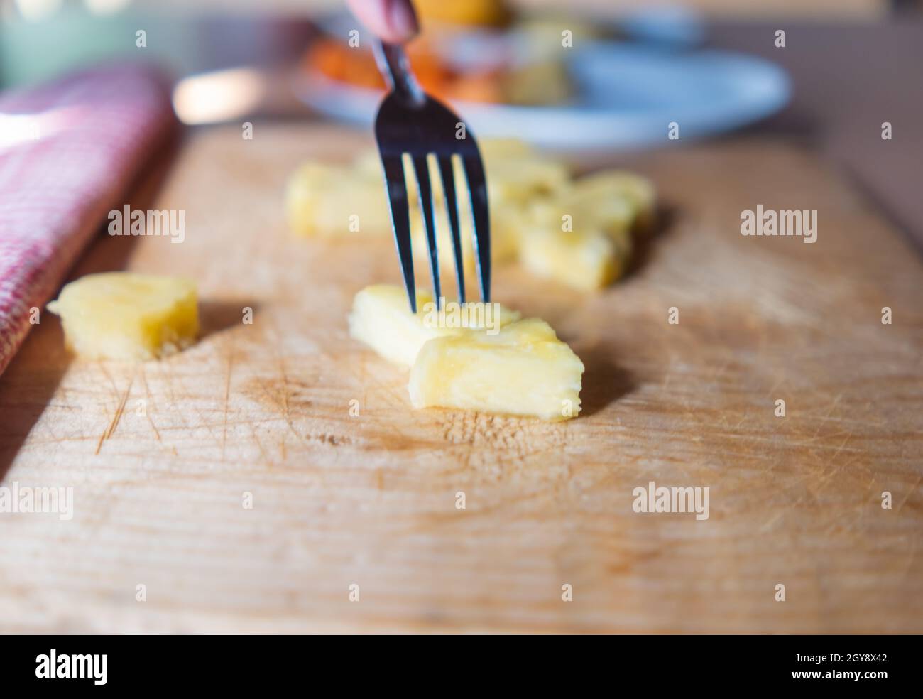Fork poking pineapple slice above wooden cutting board Stock Photo - Alamy