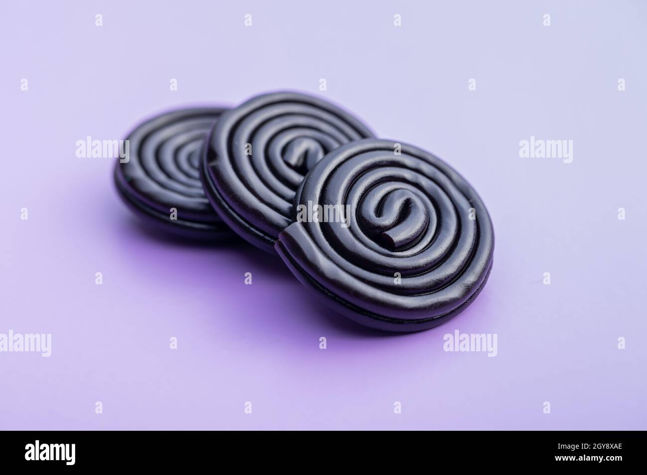 Spiral from liquorice candy on violet background Stock Photo - Alamy