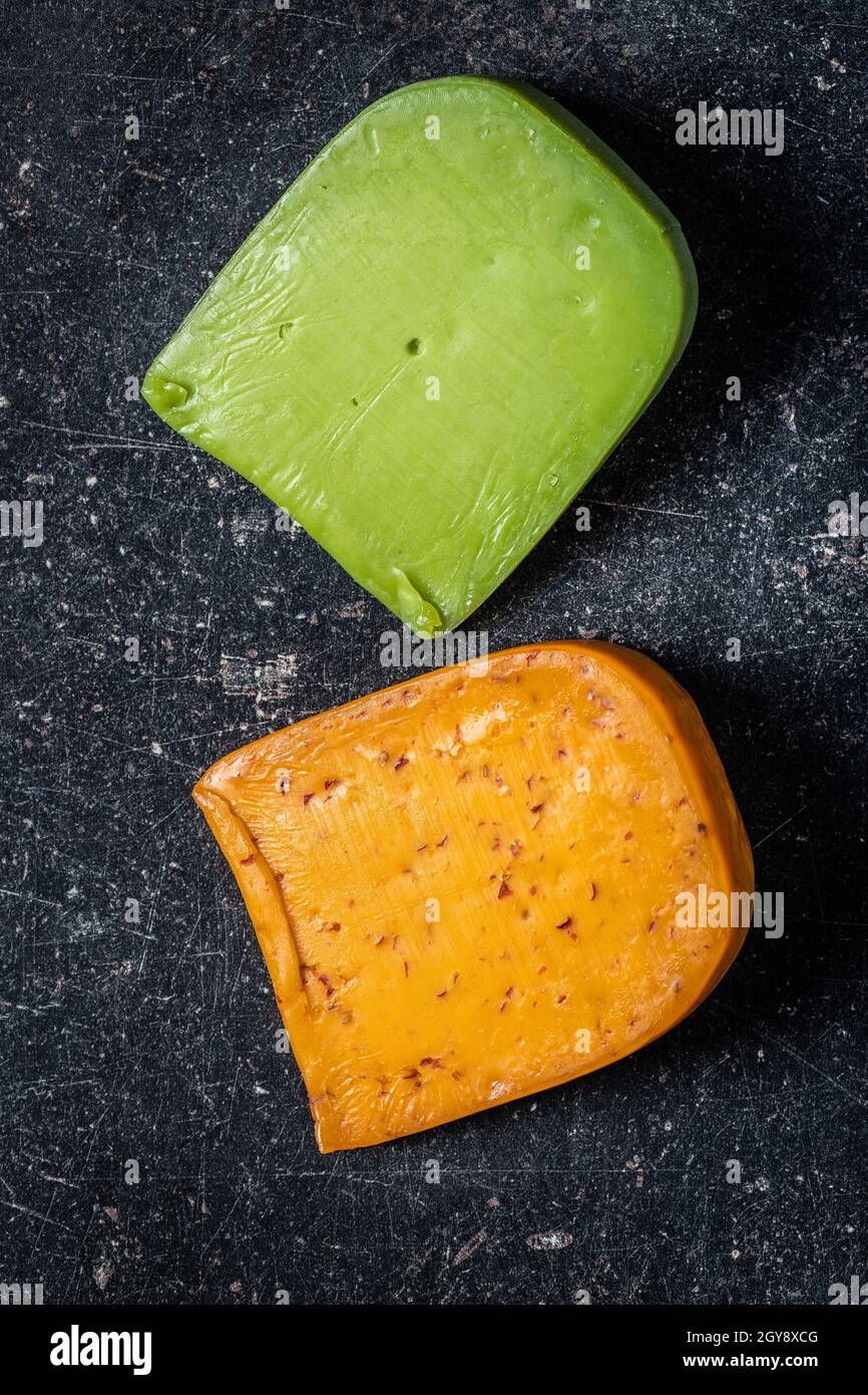 Block of hard cheese with chili and wasabi flavor on black table. Top ...