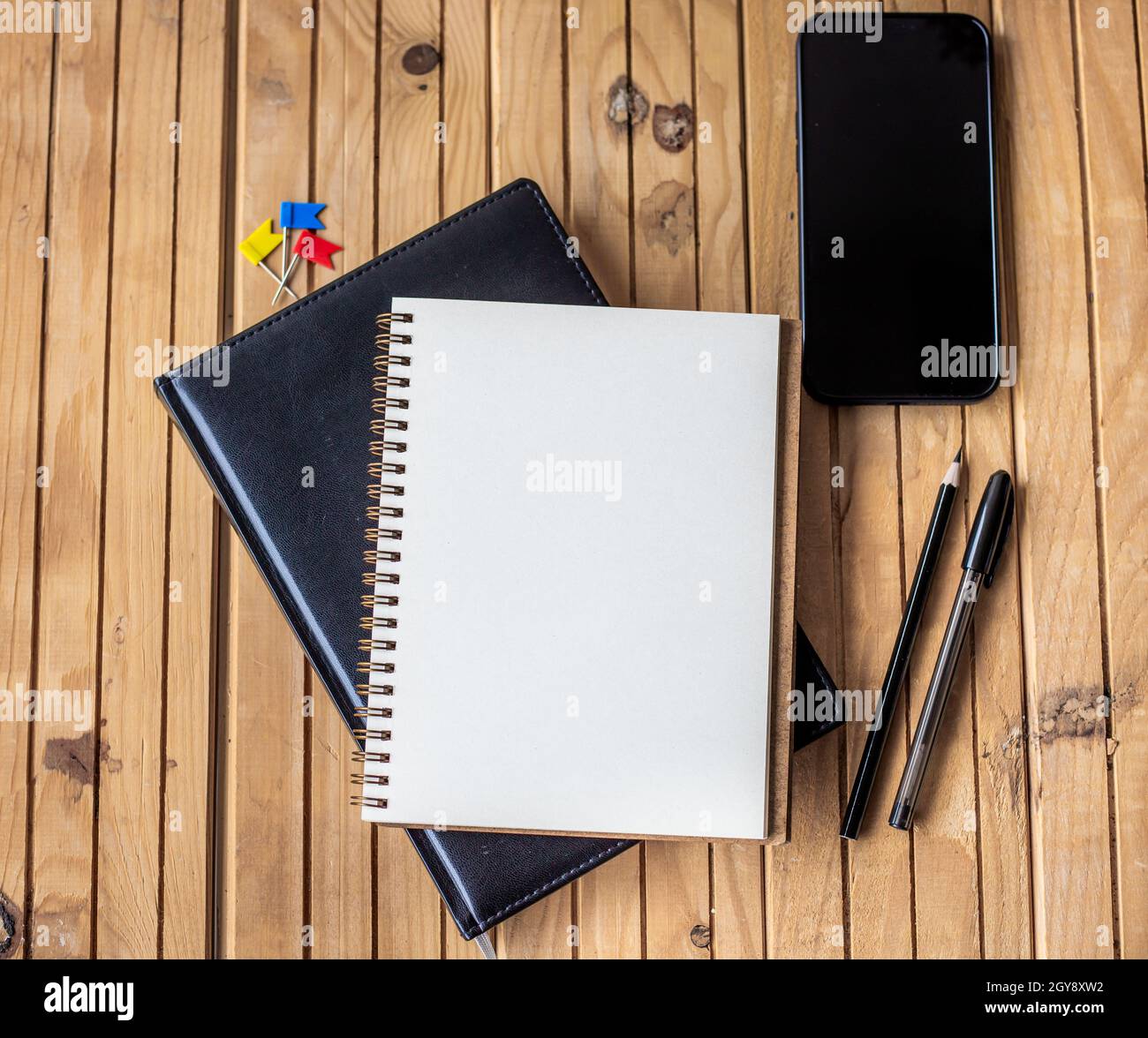 Empty Open Journal Beside Mobile With Pens On Top Of Wooden Desk Stock ...