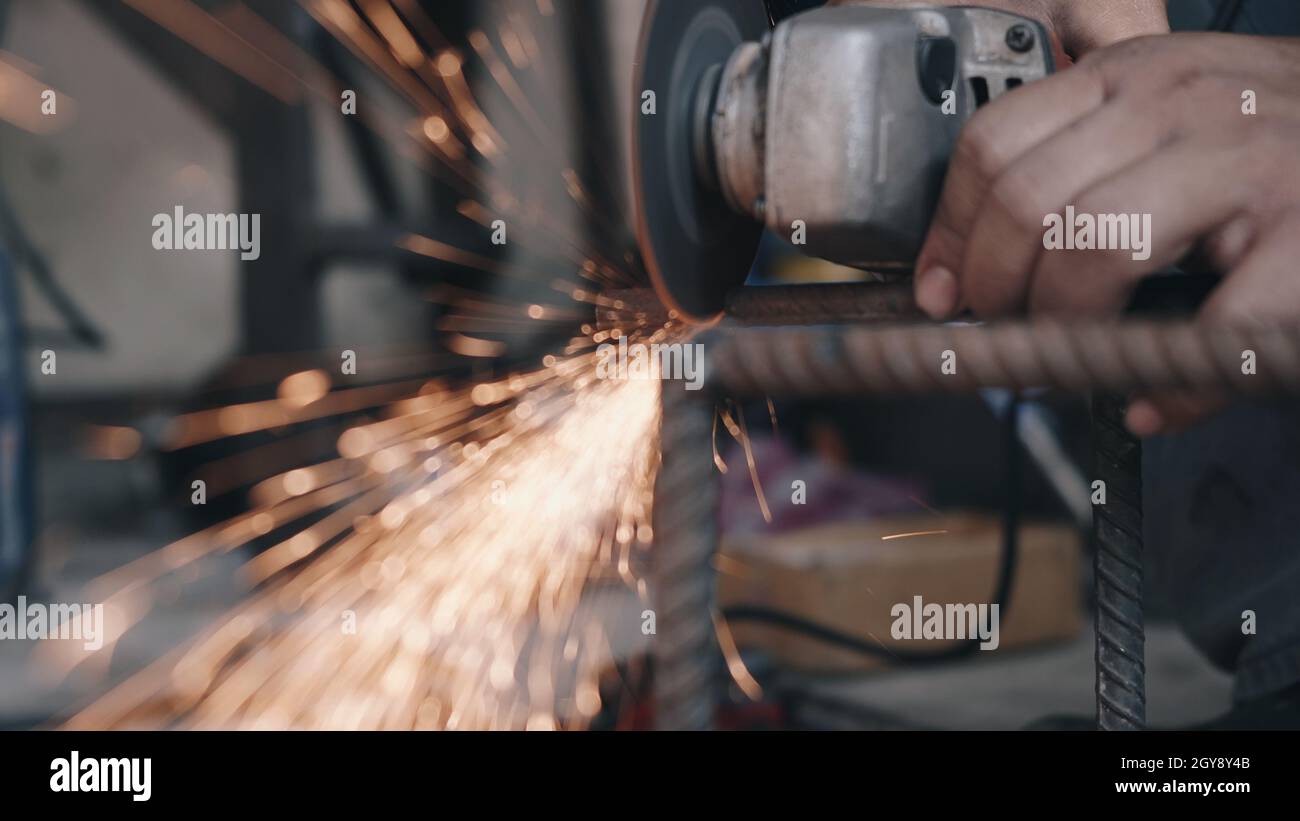 Worker man using electric wheel grinding and cutting on steel structure ...