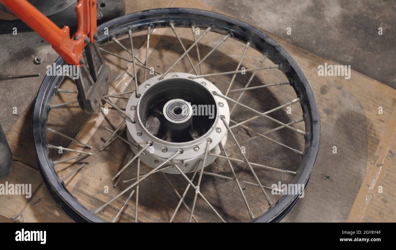 A motorcycle mechanic man using iron nippers. Cut the spokes from the ...