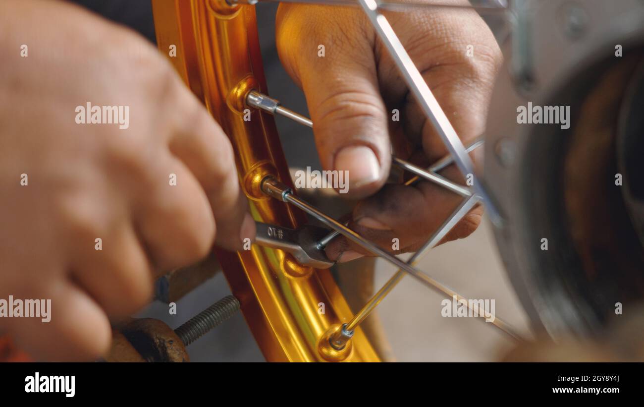 Technician man working motorcycle wheel has spokes weave up on mechanic ...