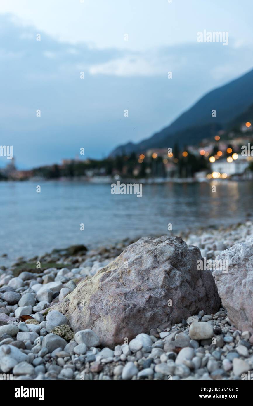 Rock in the foreground, cute little Italian village with lights in the ...