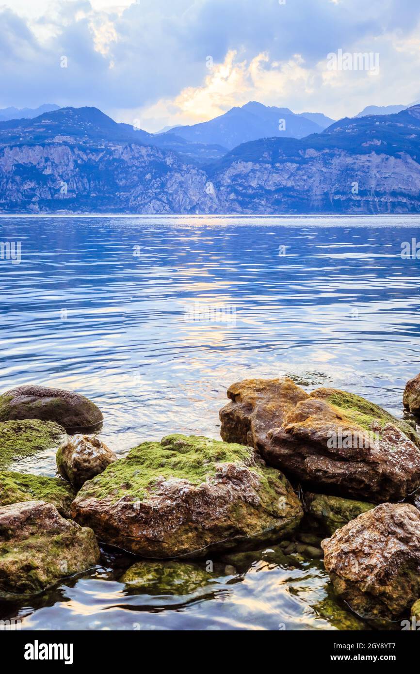 Colorful rocks and reflections in the lake Lago di Garda. Clear water ...