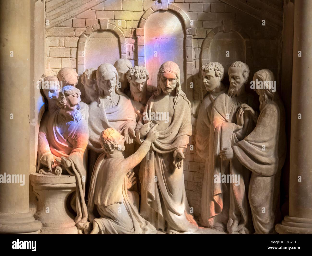 Light from a stained glass window falling on a sculpture in a church in ...
