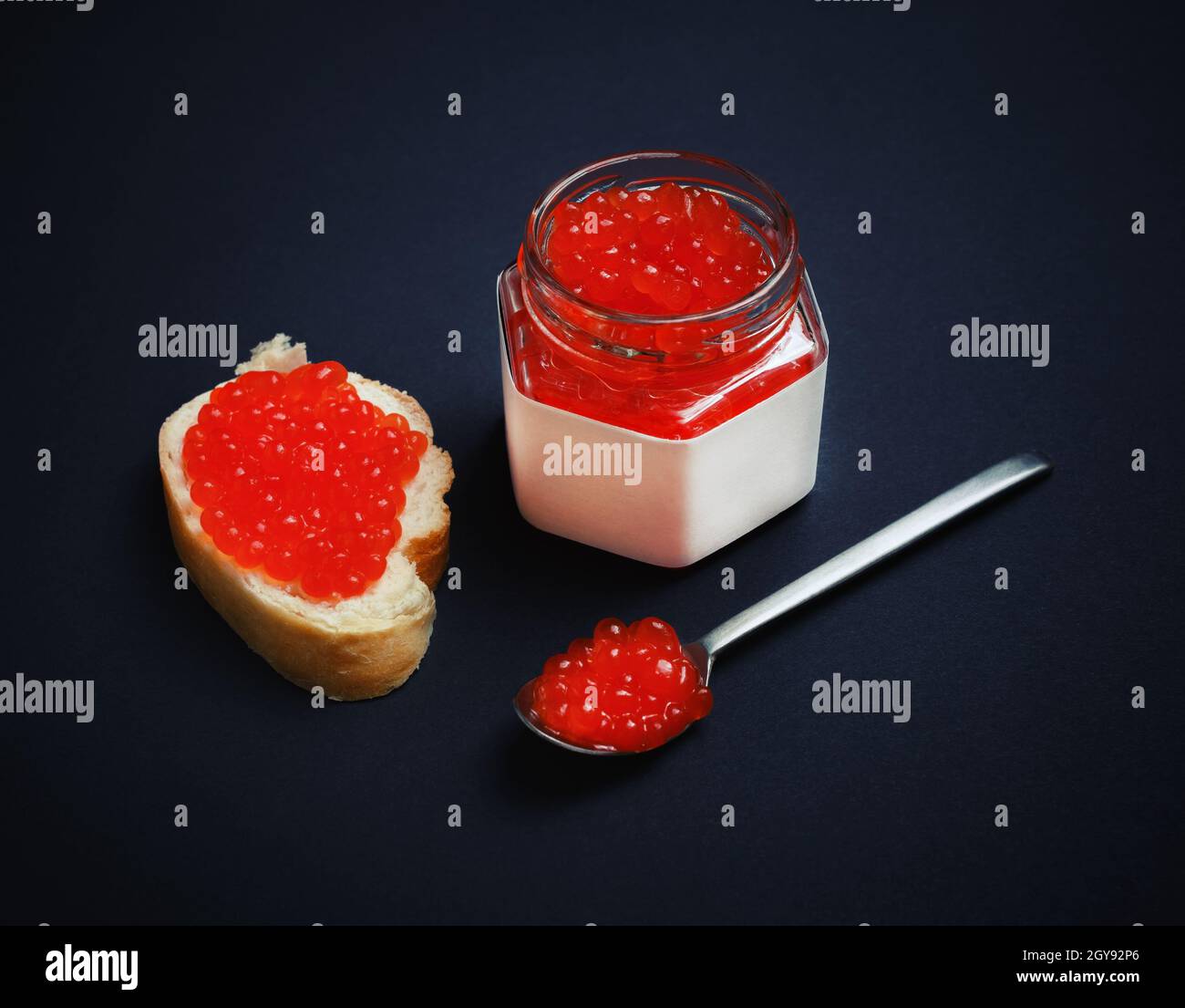 Still life with red caviar. Fresh caviar, sandwich, glass jar and spoon ...