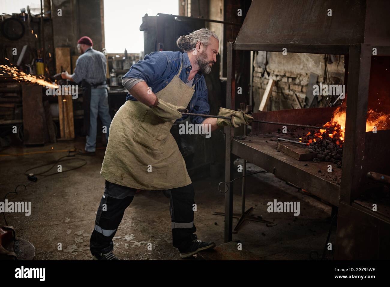 Craftsman adding coal in furnace in the blacksmith shop Stock Photo - Alamy