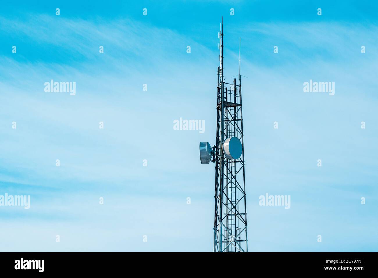 Telecommunication tower with antennas and satellite dish on clear blue sky Stock Photo - Alamy