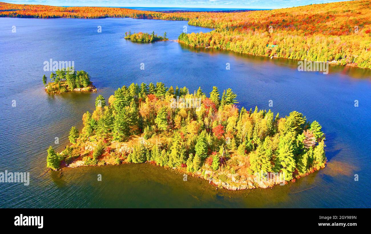 Smaller islands near a larger island of fall trees in a large lake with ...