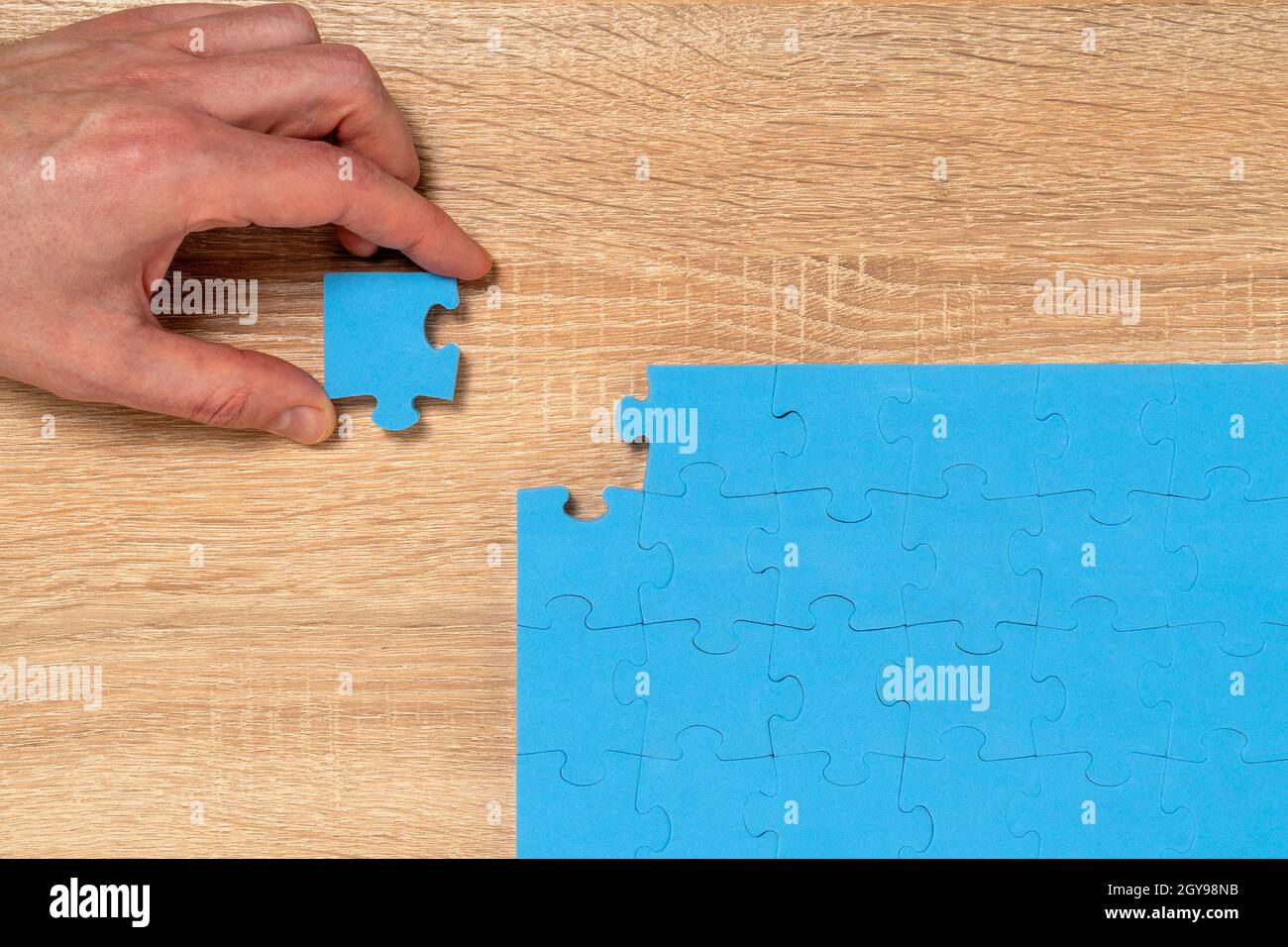 Finishing the last piece of a jigsaw puzzle game on wooden desk Stock ...