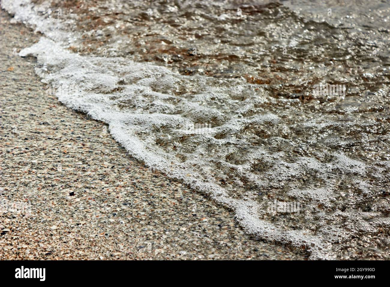 Sea foam on beach sand with clear water. Sand Beach And Sea Foam Macro ...