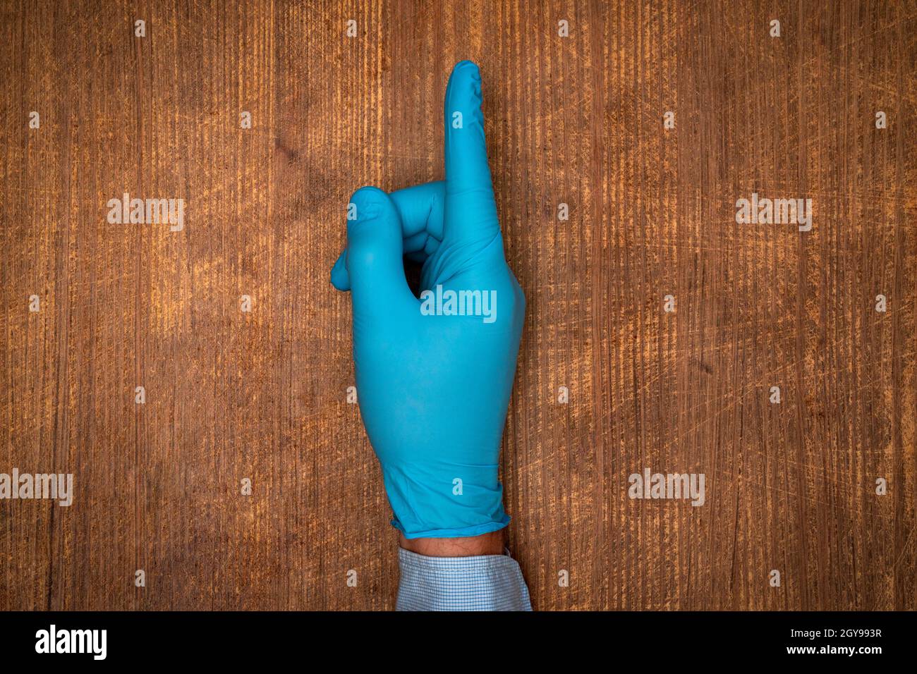 Male doctor hand in blue glove make gesture with index finger up Stock ...