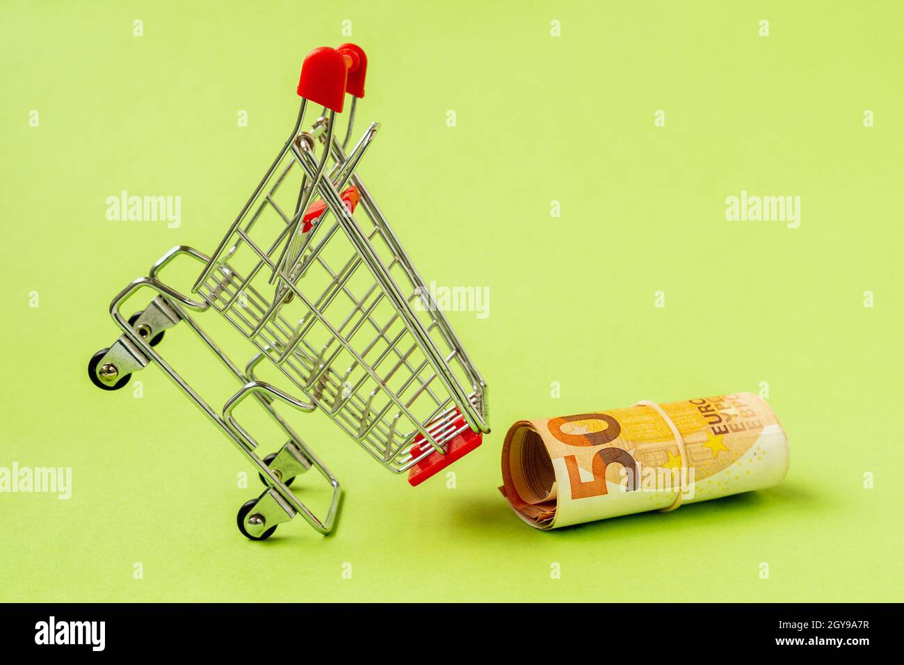 Roll of Euro currency falling from shopping cart. Financial concept ...