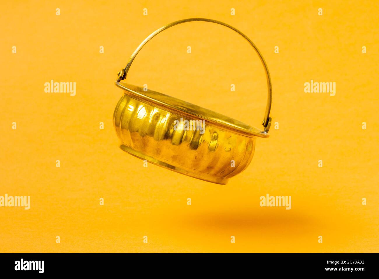 Empty golden pot falling on the yellow background Stock Photo - Alamy