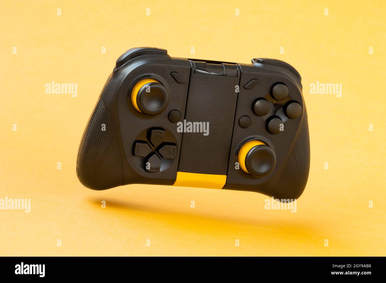 Video game controller falling on the yellow background Stock Photo - Alamy