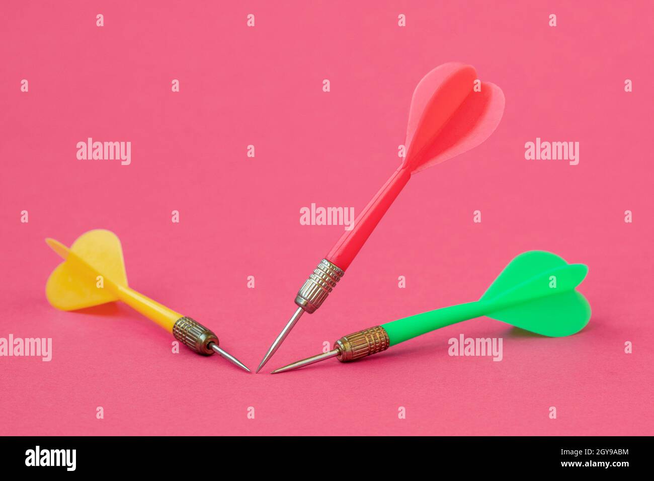 Three colored dart arrows on the pink background Stock Photo - Alamy