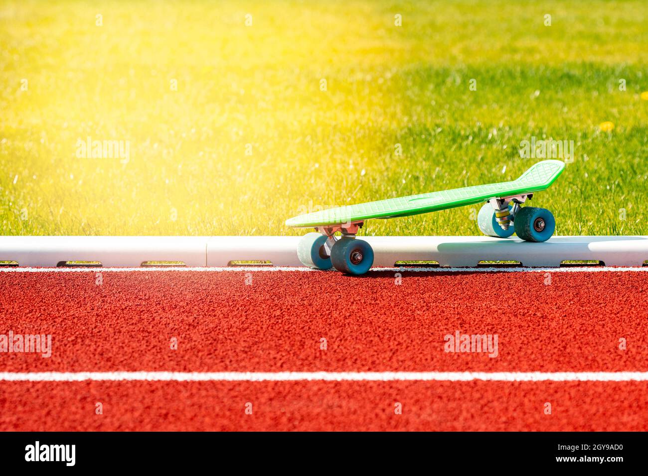 Green skateboard stands on the running track in the school stadium ...