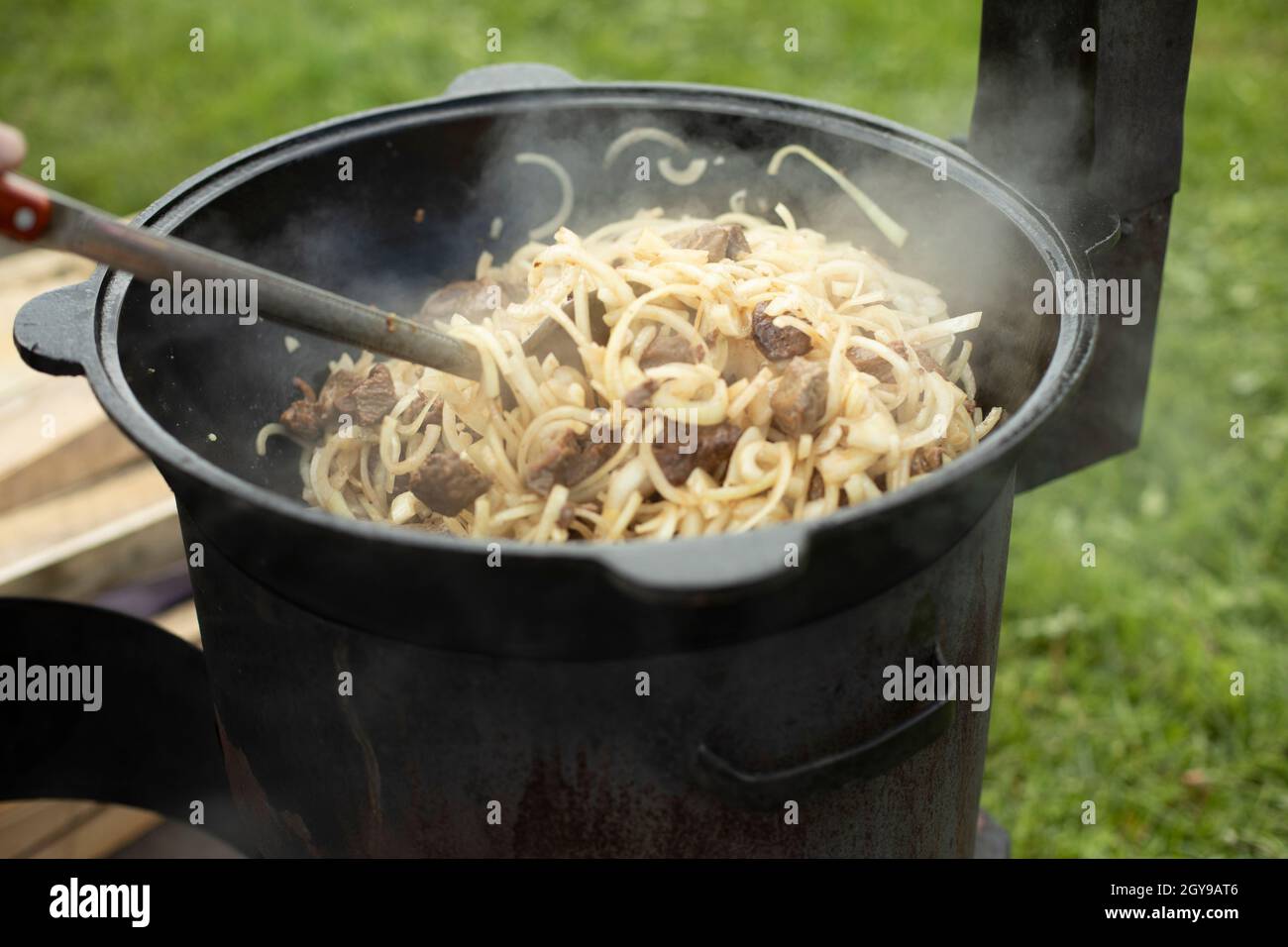 Cooking pilaf. The food is fried in a frying pan. Lunch in nature ...
