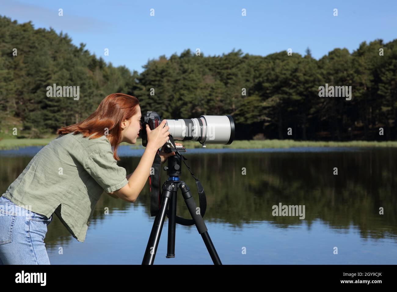 Side view portrait of a photographer taking photo with telephoto and ...