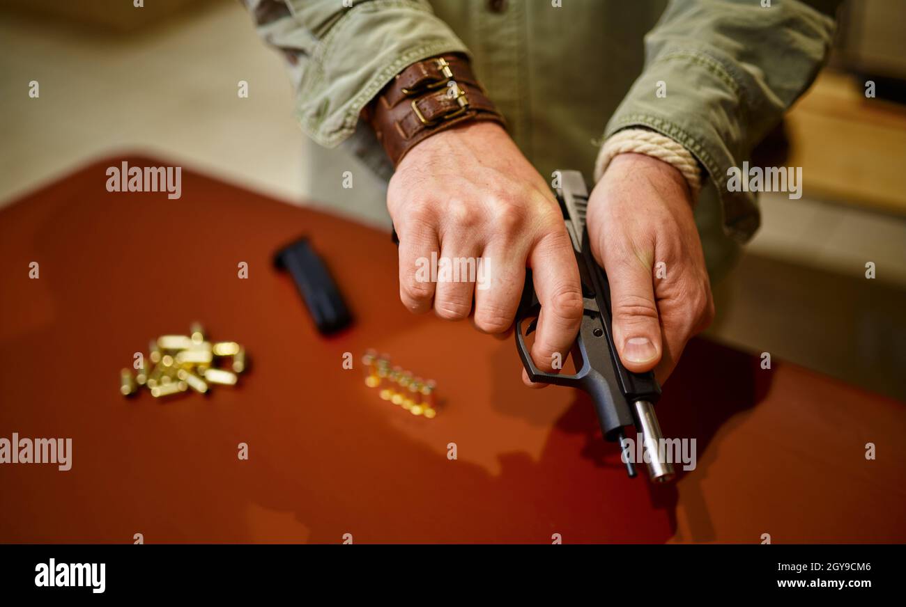 Man loads the gun with bullets in gun store. Weapon shop interior, ammo ...
