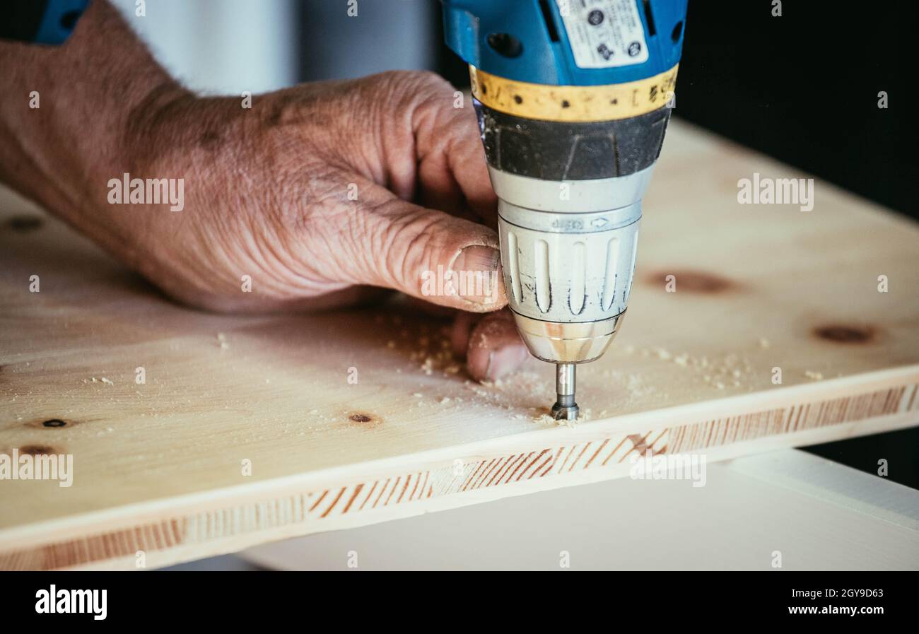 Craftsman is drilling in wood with drilling machine Stock Photo - Alamy
