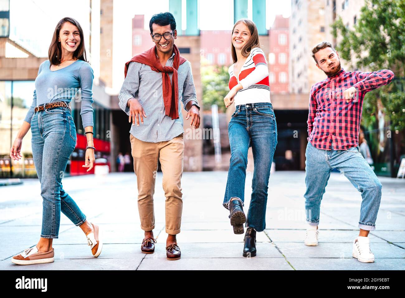 Multicultural friends walking at city center acting funny crazy moves ...