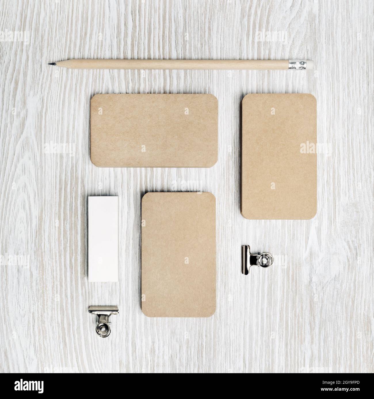 Blank kraft business cards, pencil and eraser on light wood table ...