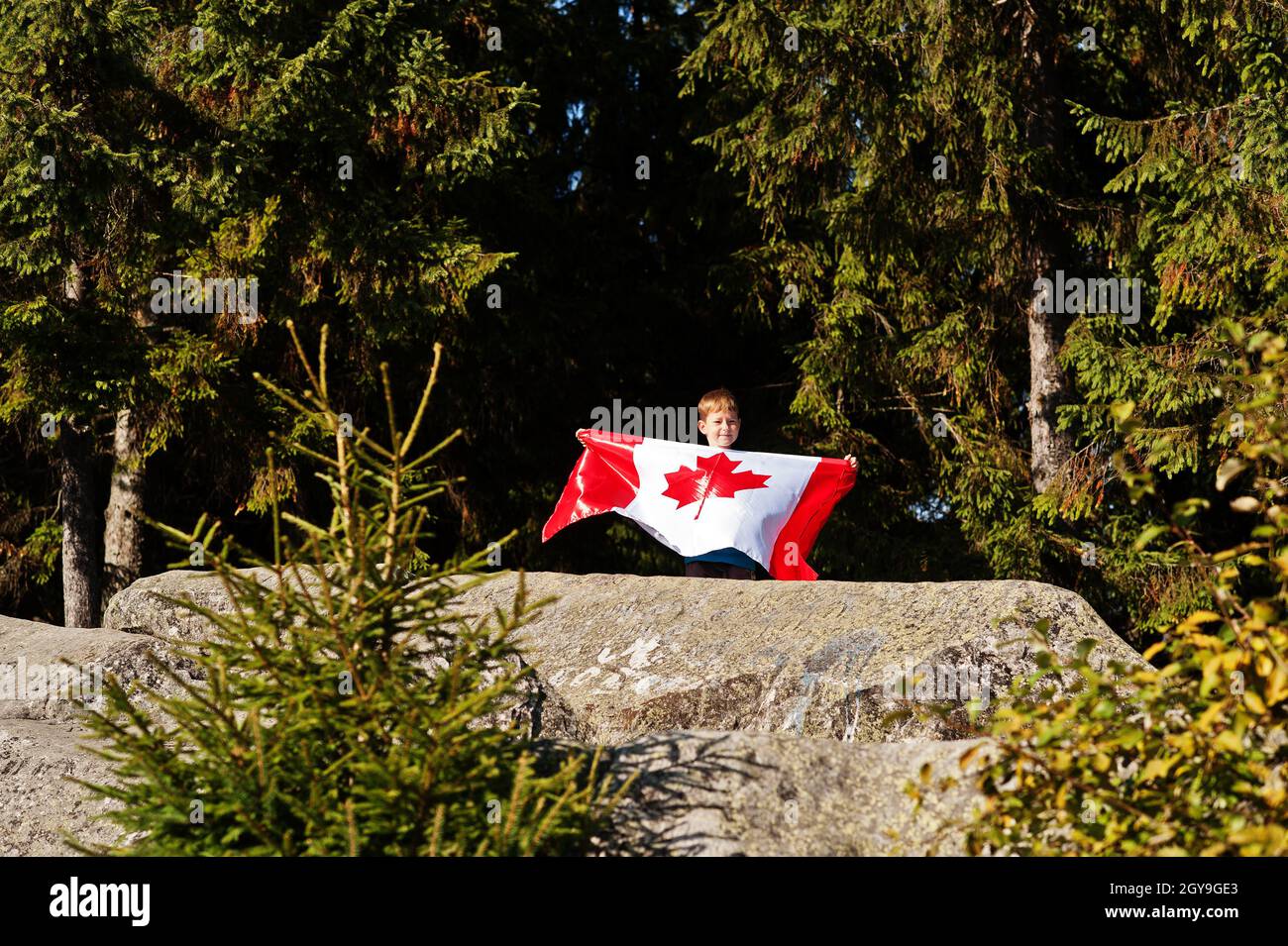 Happy Canada Day. Boy with large Canadian flag celebration in mountains ...