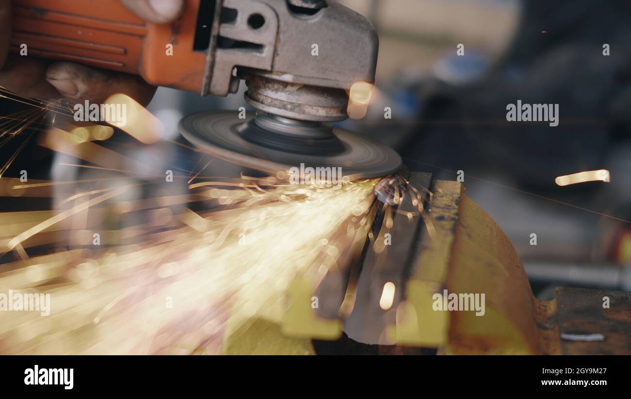 Worker man using electric wheel tool grinding and cutting on steel ...