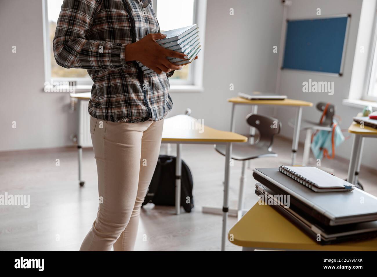 Female teacher holding many books in classroom Stock Photo - Alamy