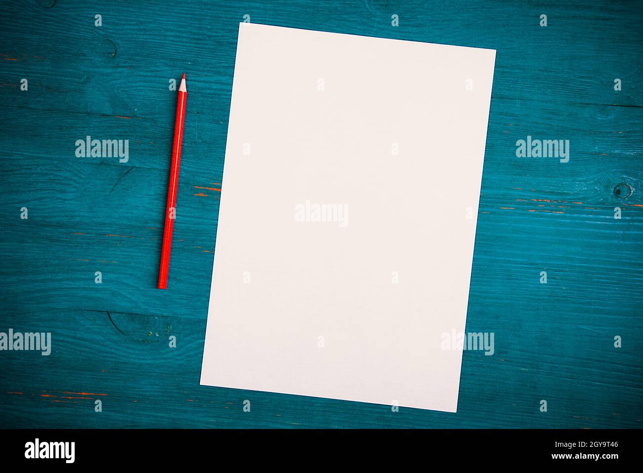 A blank white sheet and pencil for drawing on a wooden background with ...