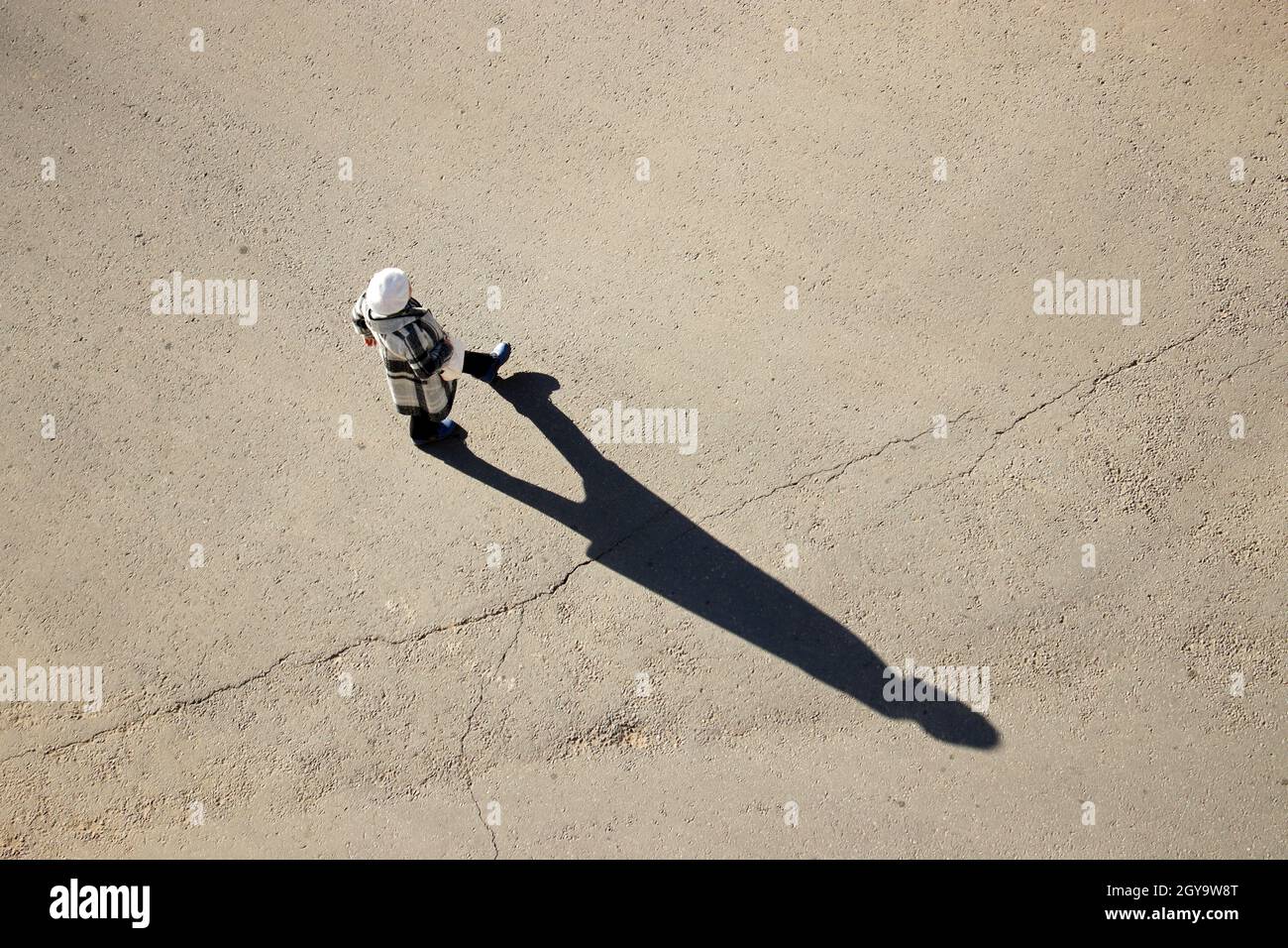 Woman crossing the street, top view, long shadow on asphalt. Concept of ...