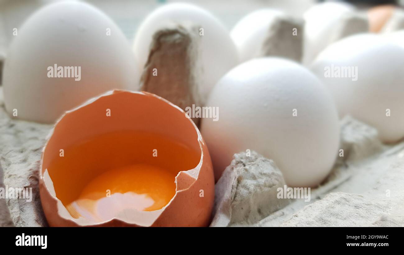 A chicken egg is half broken among other eggs. Close-ups in a paper ...