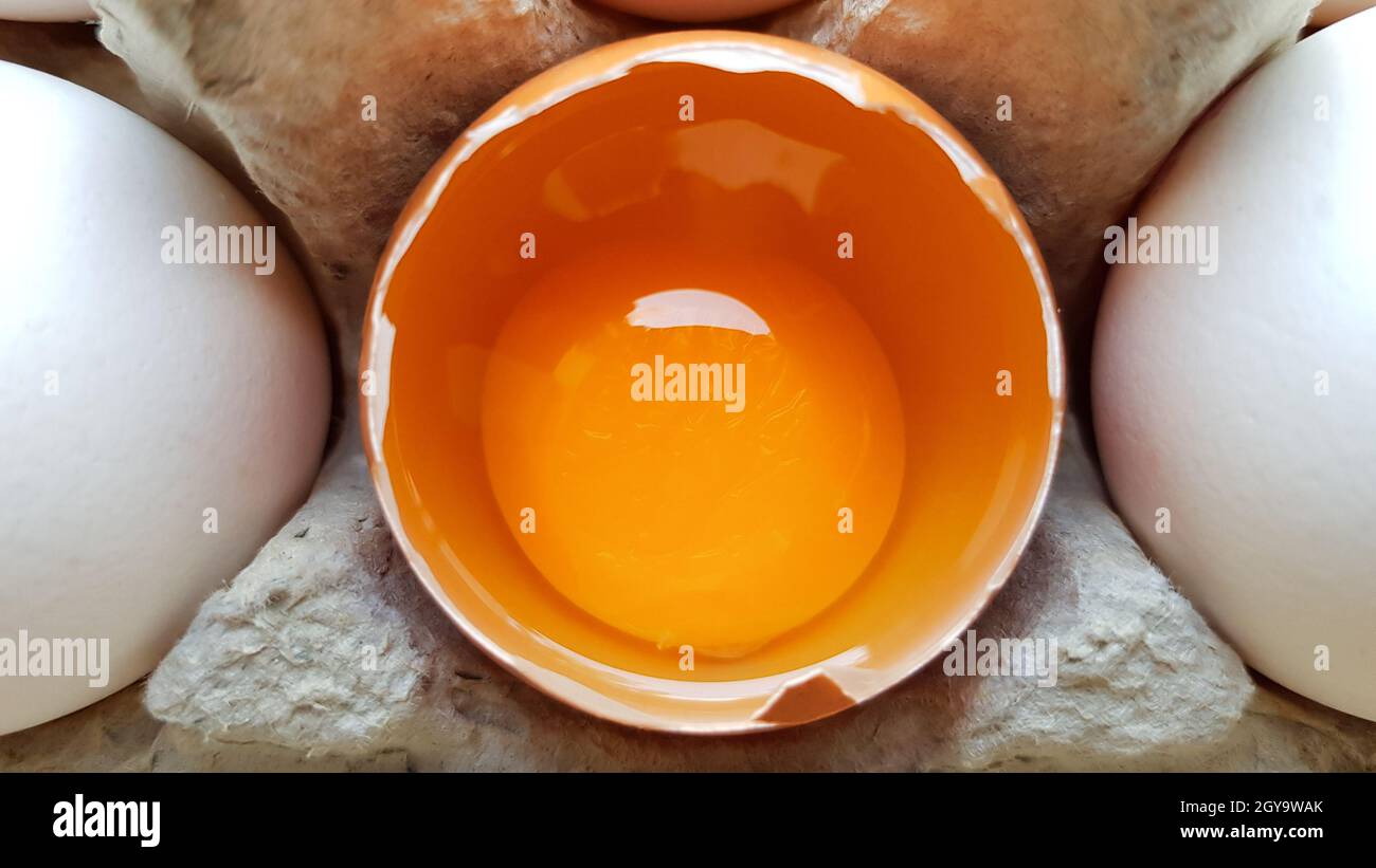 A chicken egg is half broken among other eggs. Close-ups in a paper ...