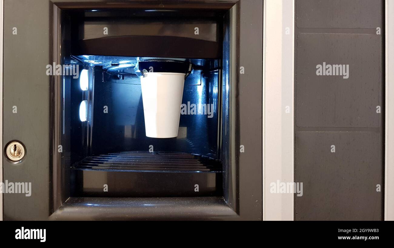 White paper cup in the window of a vending coffee machine. The process ...