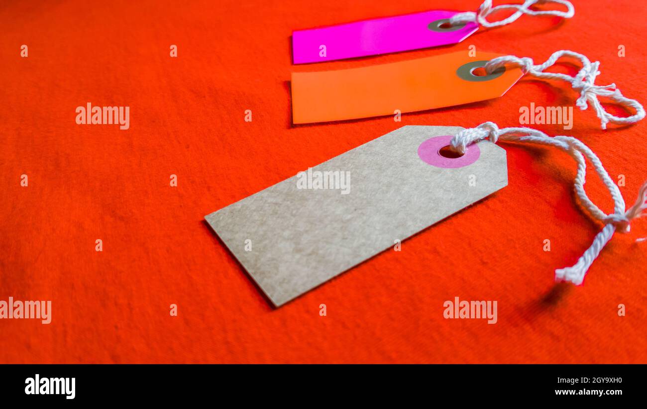 three colored tags on a white rope, red background Stock Photo - Alamy